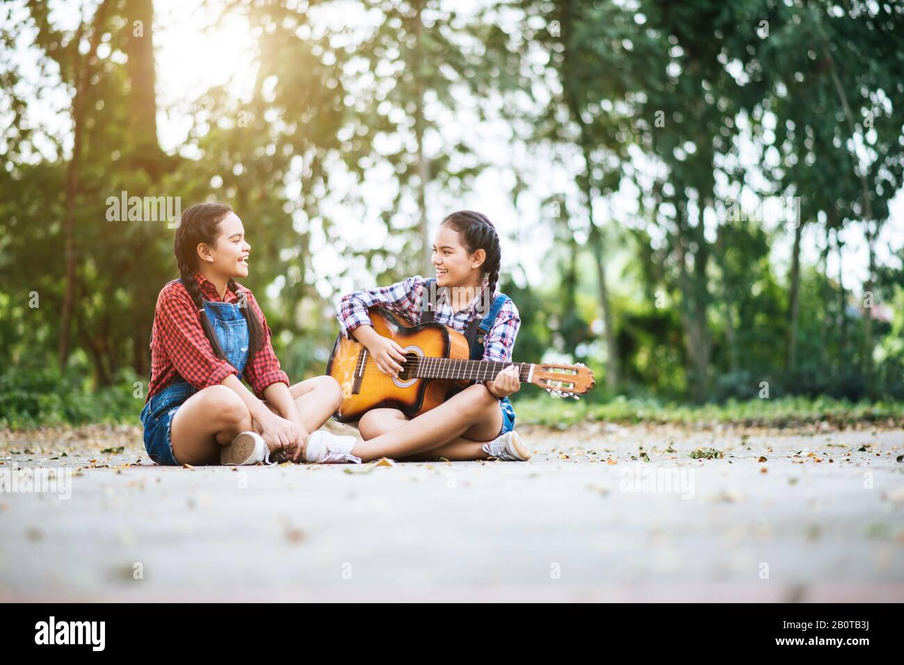 Two girl relax playing guitar and sing a song Stock Photo - Alamy
