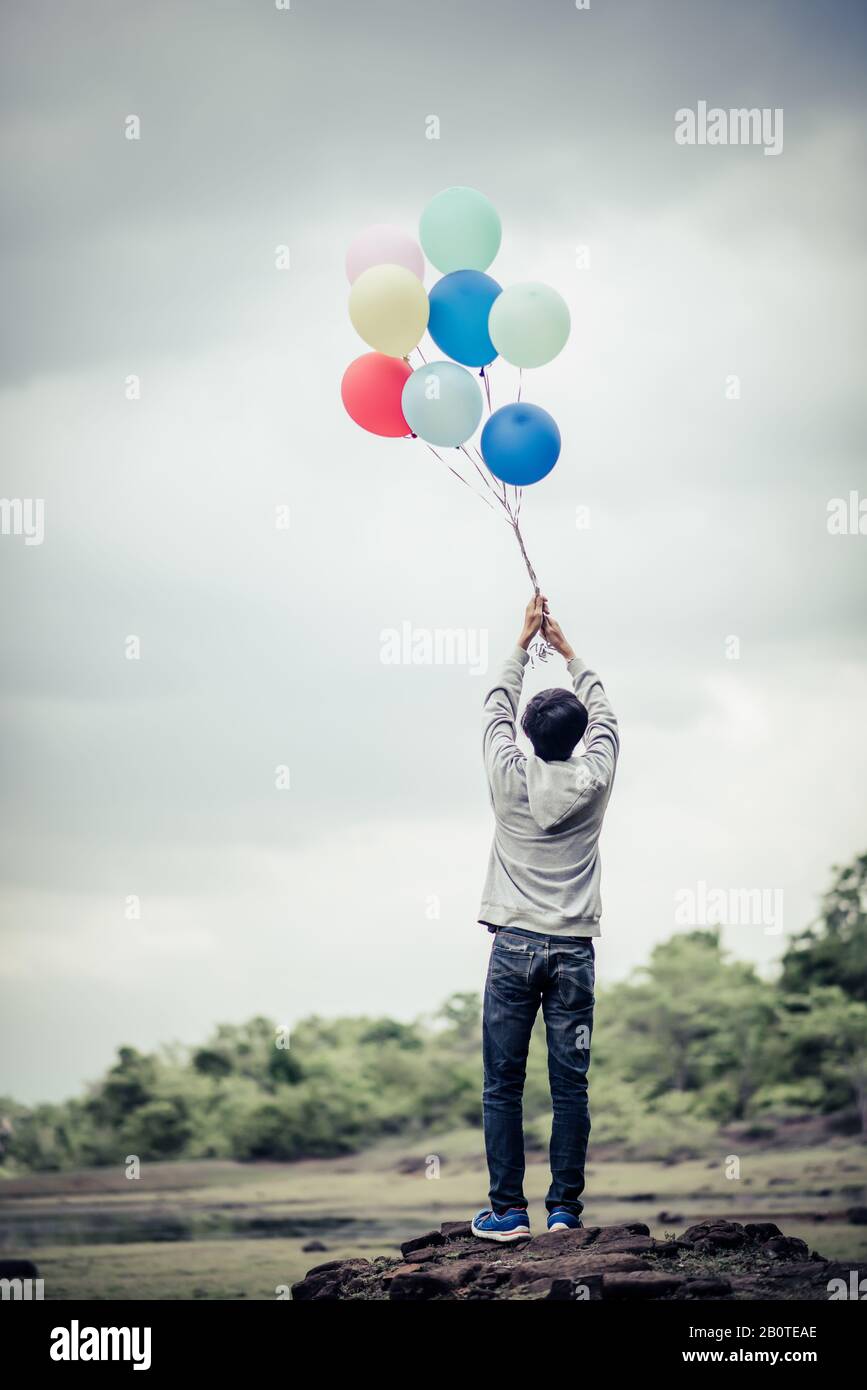 Young man hand holding colorful balloons Stock Photo - Alamy