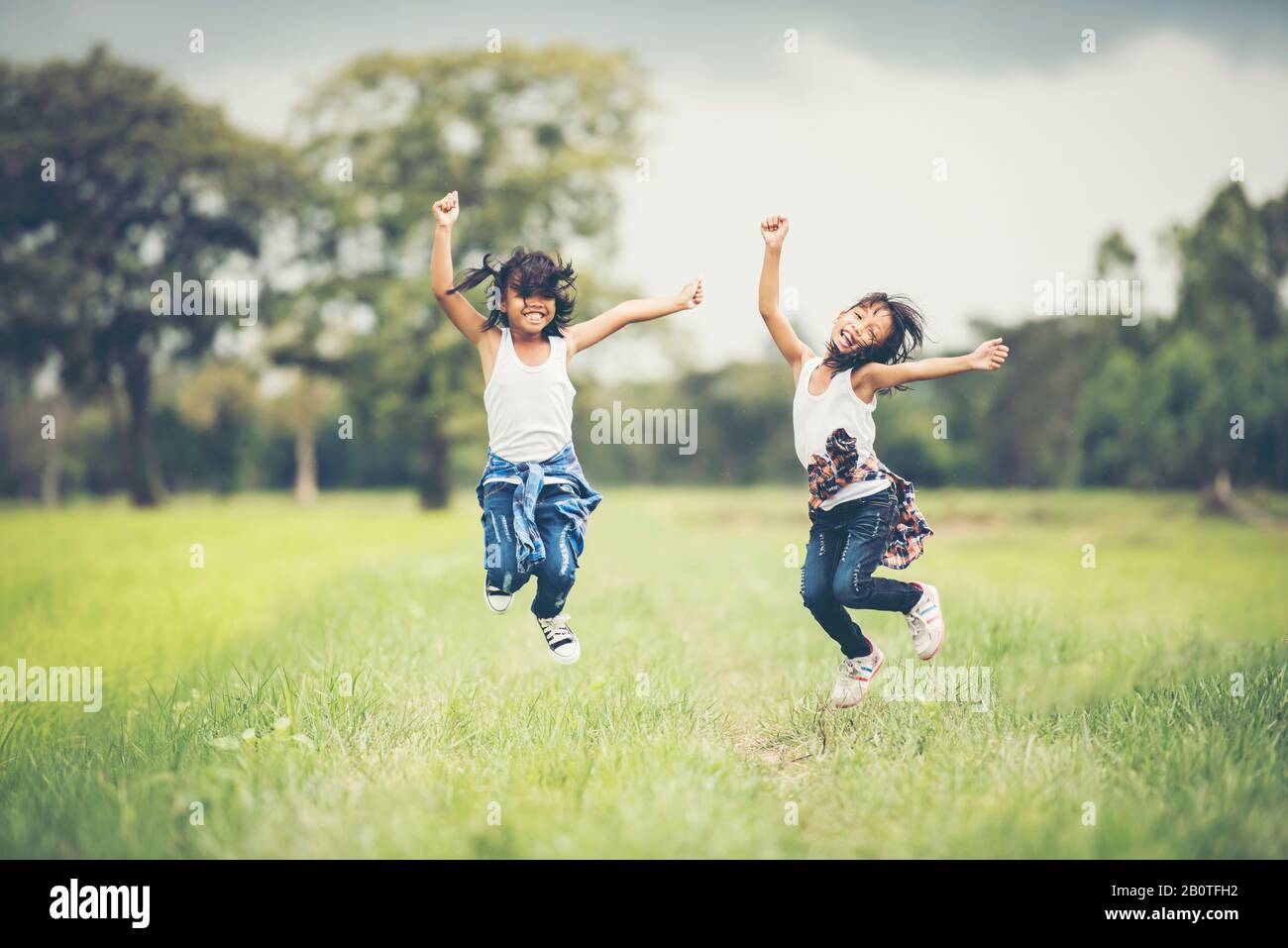 Two little girls happy jump in the nature park Stock Photo - Alamy
