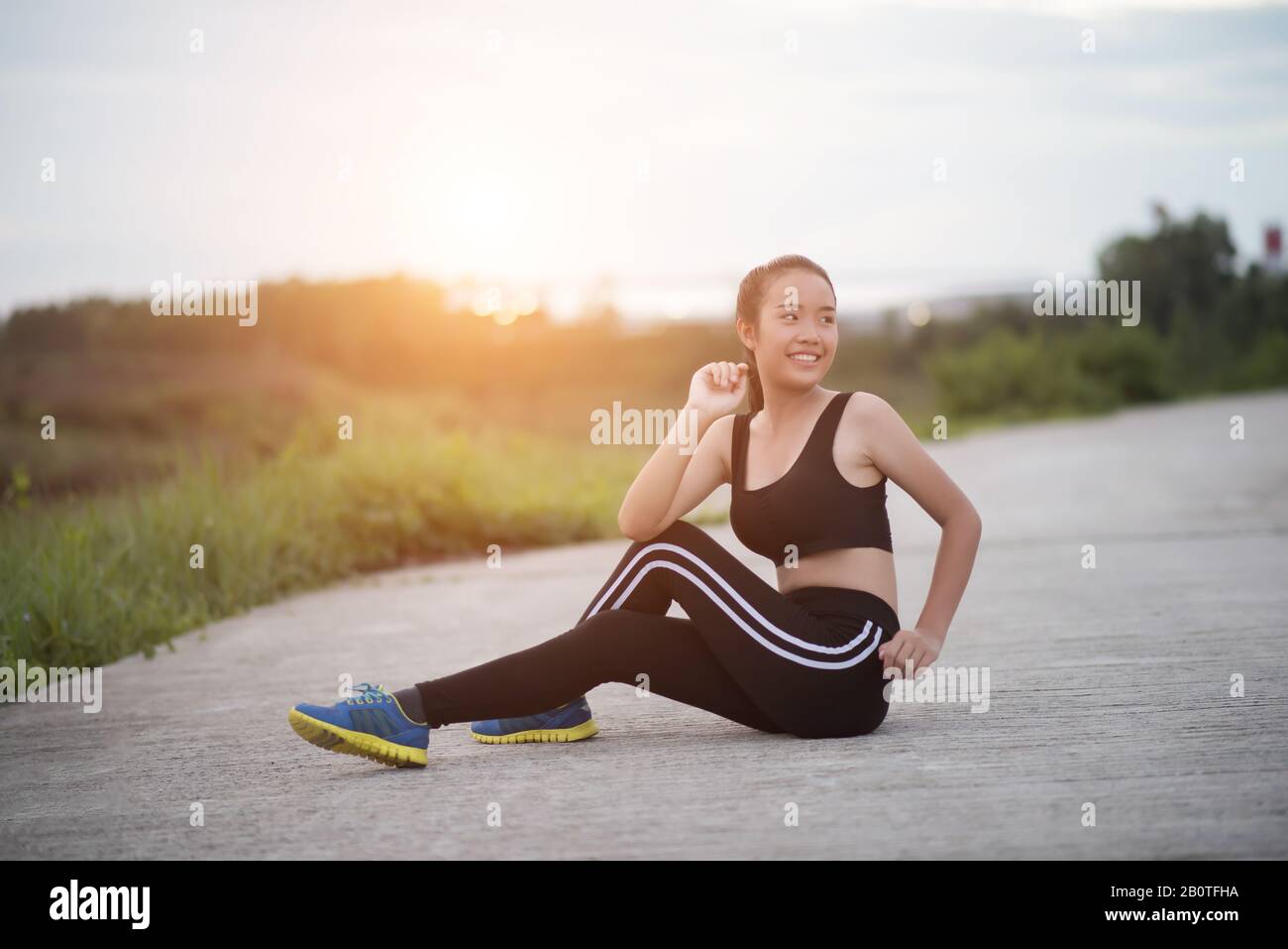 Fitness woman runner sit down relaxing with water bottle after training ...