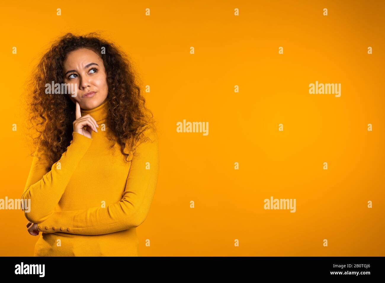 Thinking woman looking up and around on yellow background. Worried face ...
