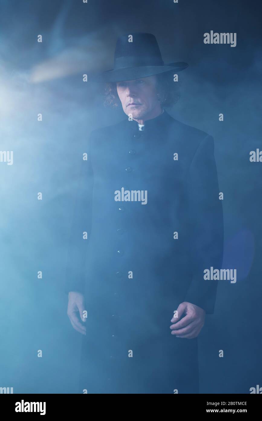 Mysterious victorian priest in black coat and hat in fog Stock Photo ...