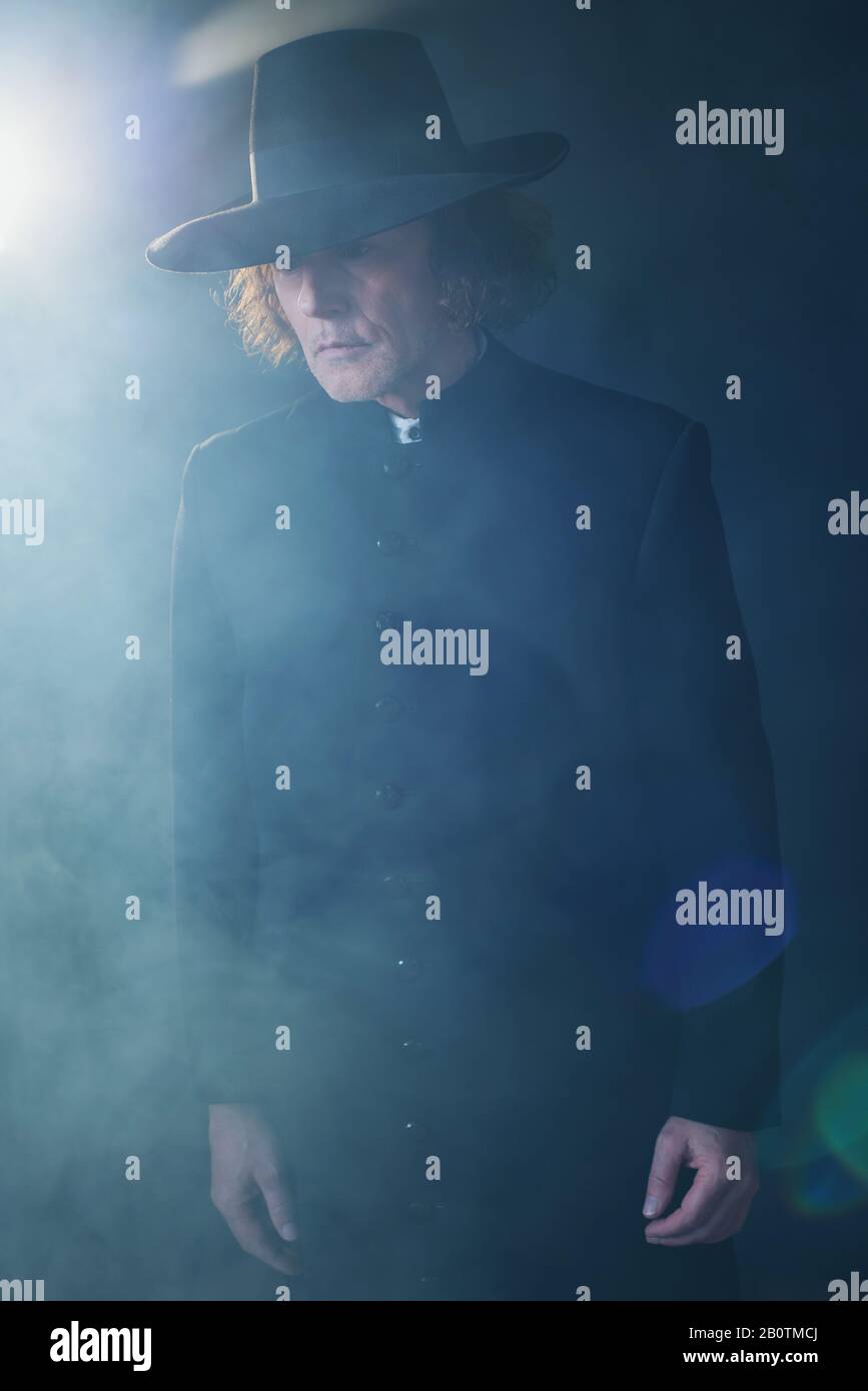 Mysterious victorian priest in black coat and hat in fog Stock Photo ...