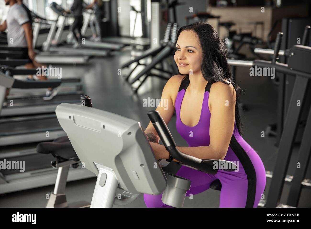 Upcoming. Young muscular caucasian woman practicing in gym with cardio ...