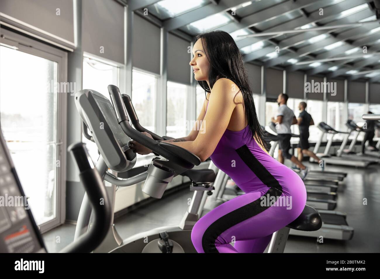 Upcoming. Young muscular caucasian woman practicing in gym with cardio ...
