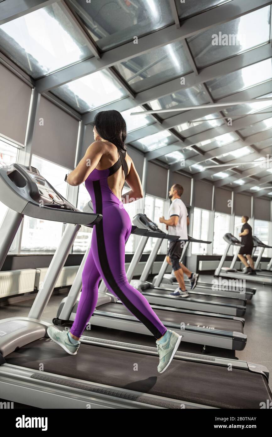 Running. Young muscular caucasian woman practicing in gym with cardio ...