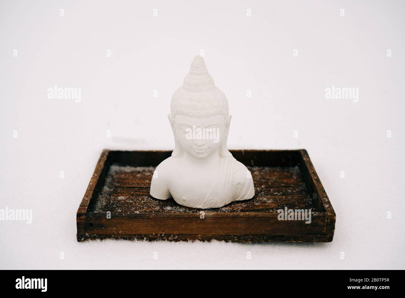 white Buddha figurine made of plaster on a wooden stand during a ...