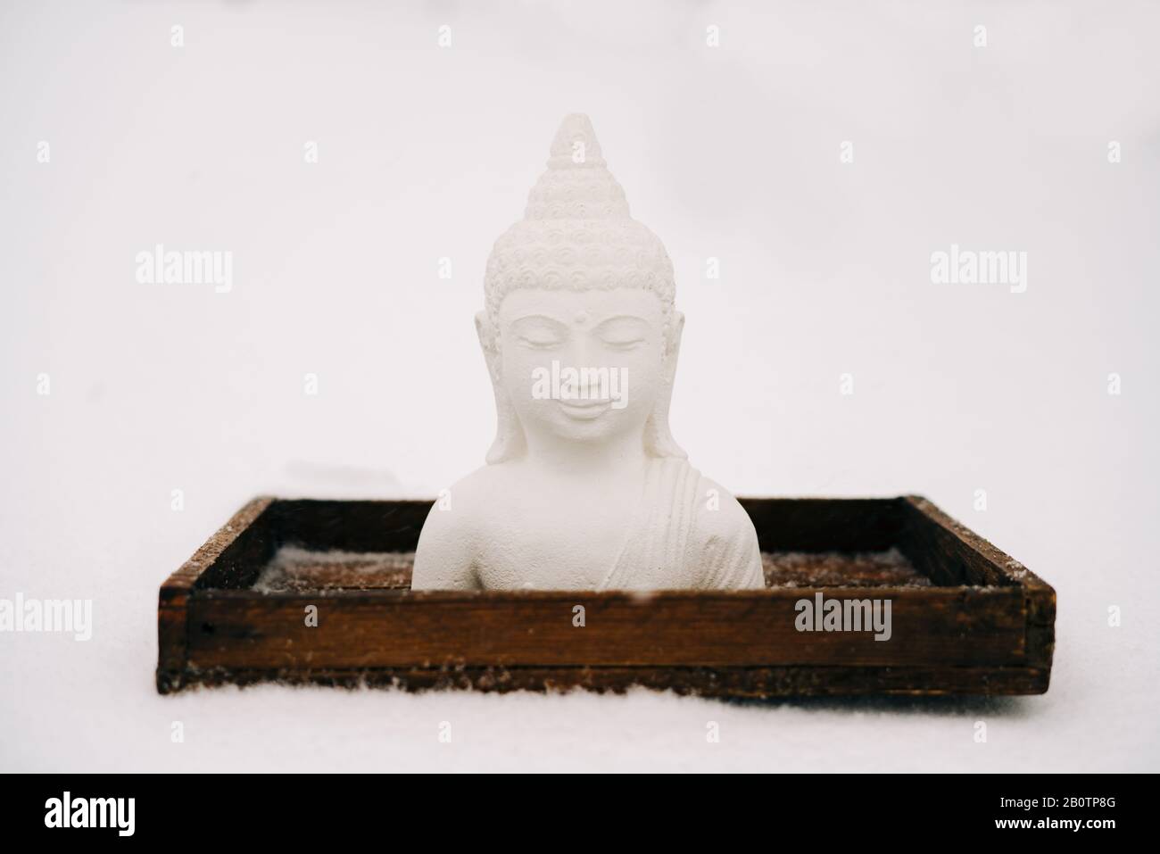 white Buddha figurine made of plaster on a wooden stand during a ...