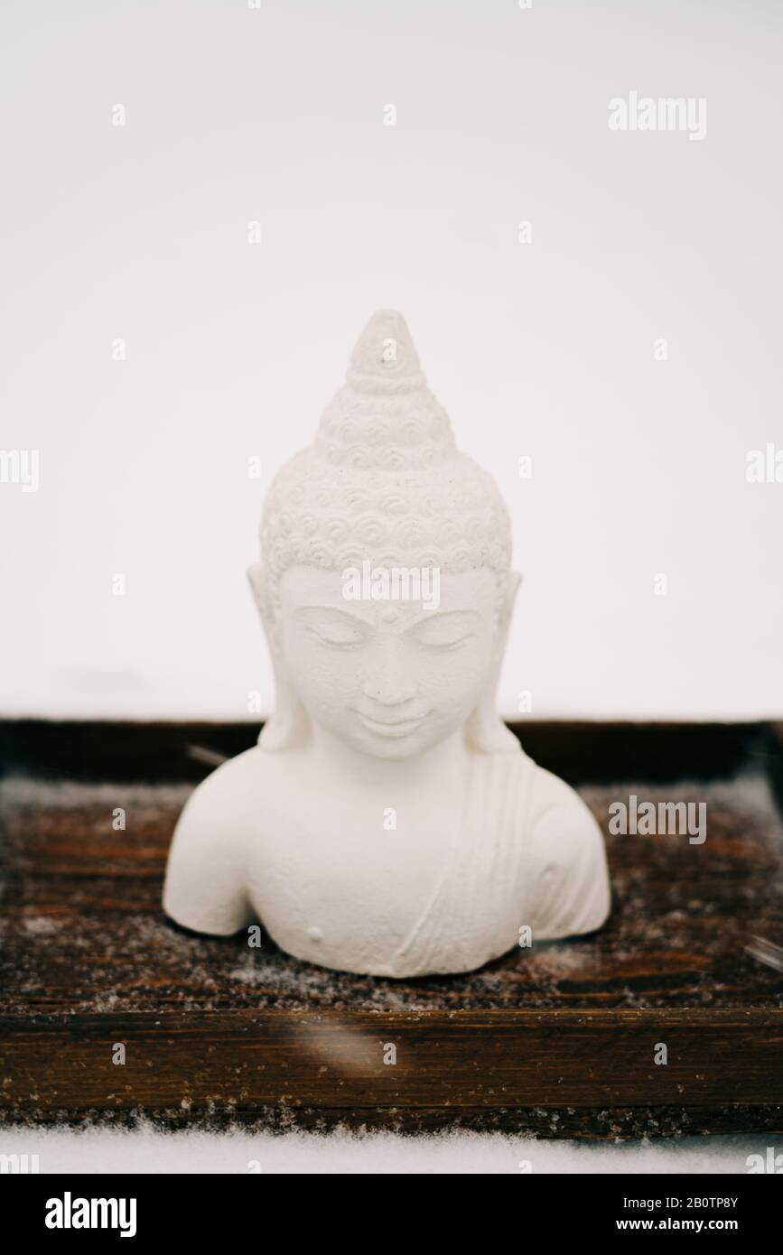 white Buddha figurine made of plaster on a wooden stand during a ...