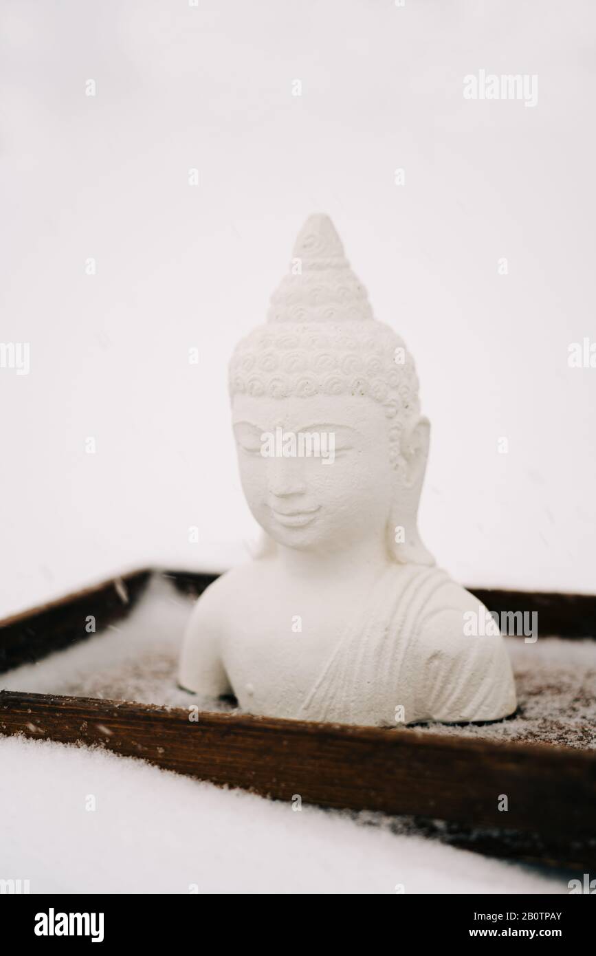 white Buddha figurine made of plaster on a wooden stand during a ...