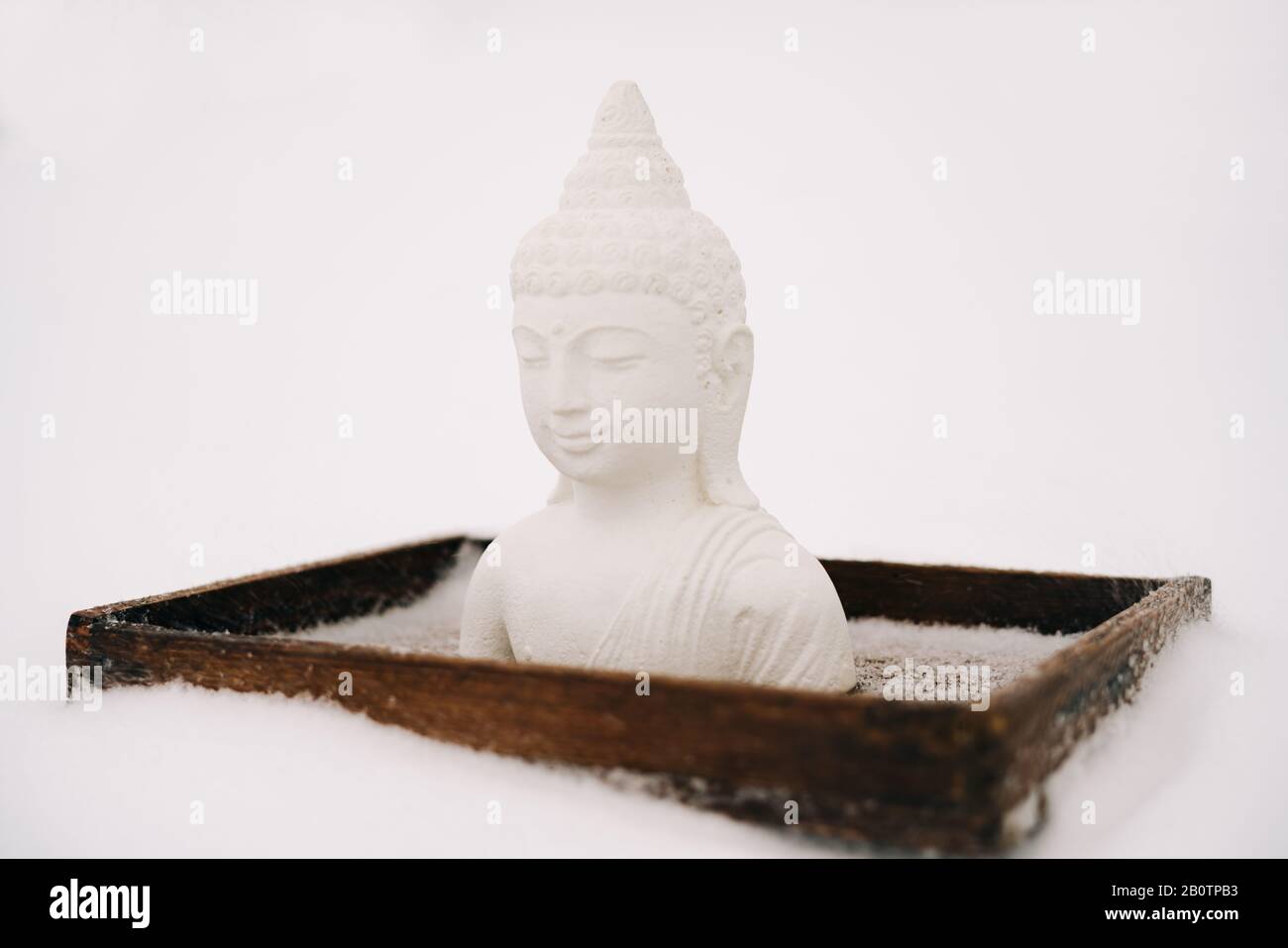 white Buddha figurine made of plaster on a wooden stand during a ...