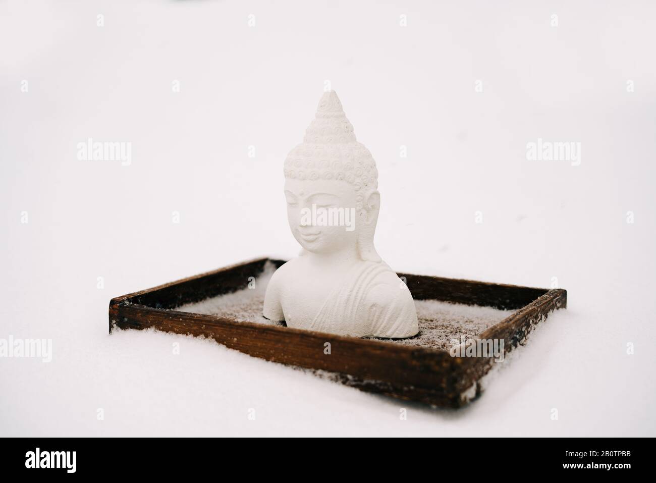 white Buddha figurine made of plaster on a wooden stand during a ...