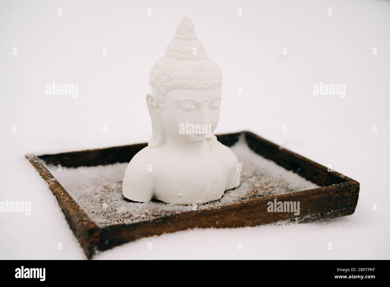 white Buddha figurine made of plaster on a wooden stand during a ...