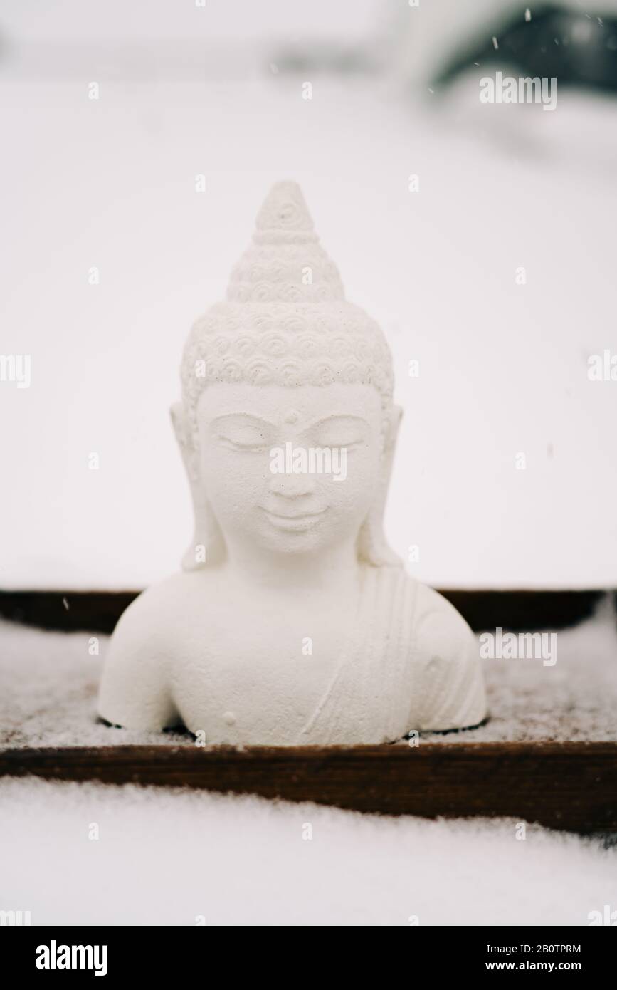 white Buddha figurine made of plaster on a wooden stand during a ...