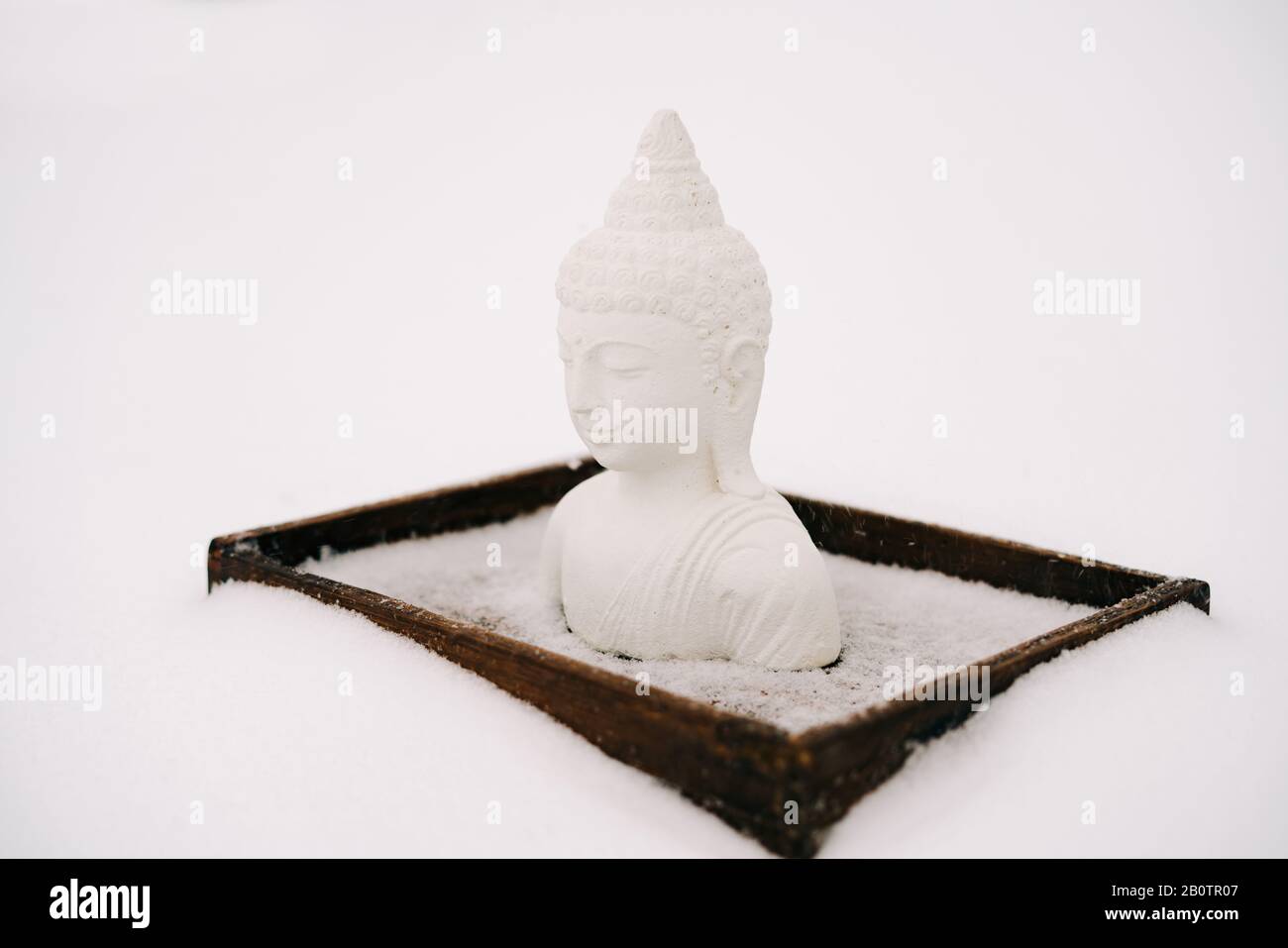 white Buddha figurine made of plaster on a wooden stand during a ...