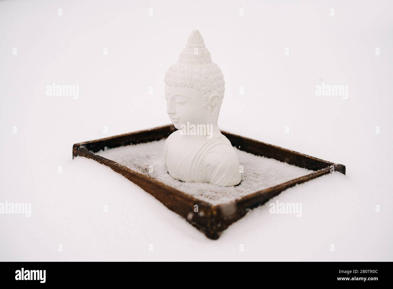 white Buddha figurine made of plaster on a wooden stand during a ...