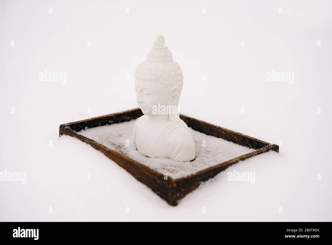 white Buddha figurine made of plaster on a wooden stand during a ...