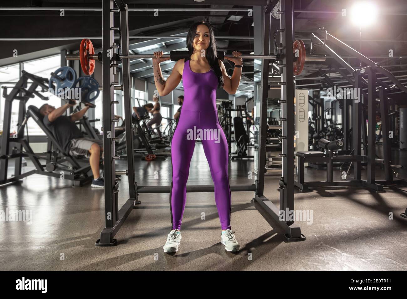 Strong. Young muscular caucasian woman practicing in gym with equipment ...