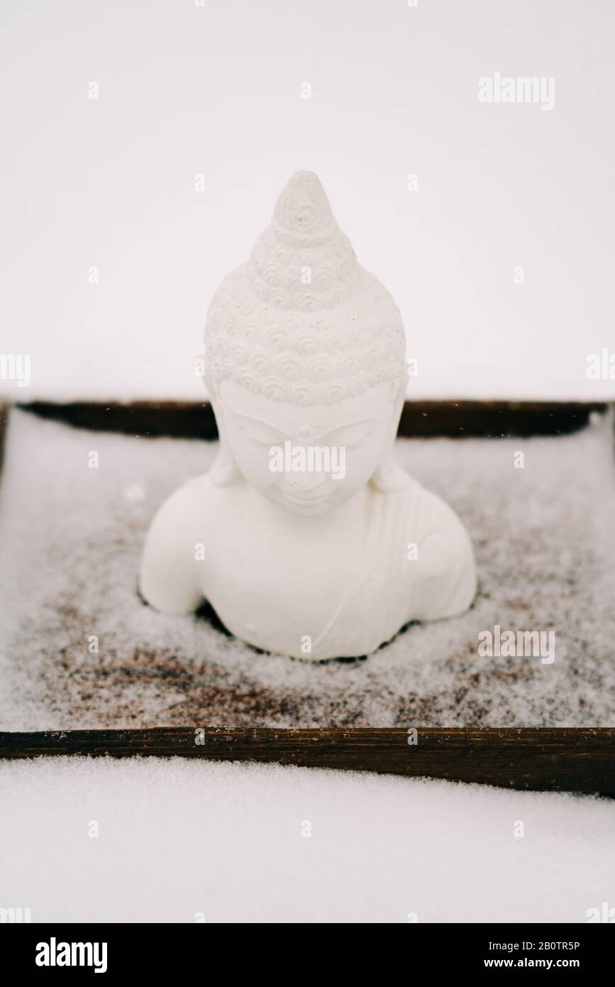 white Buddha figurine made of plaster on a wooden stand during a ...