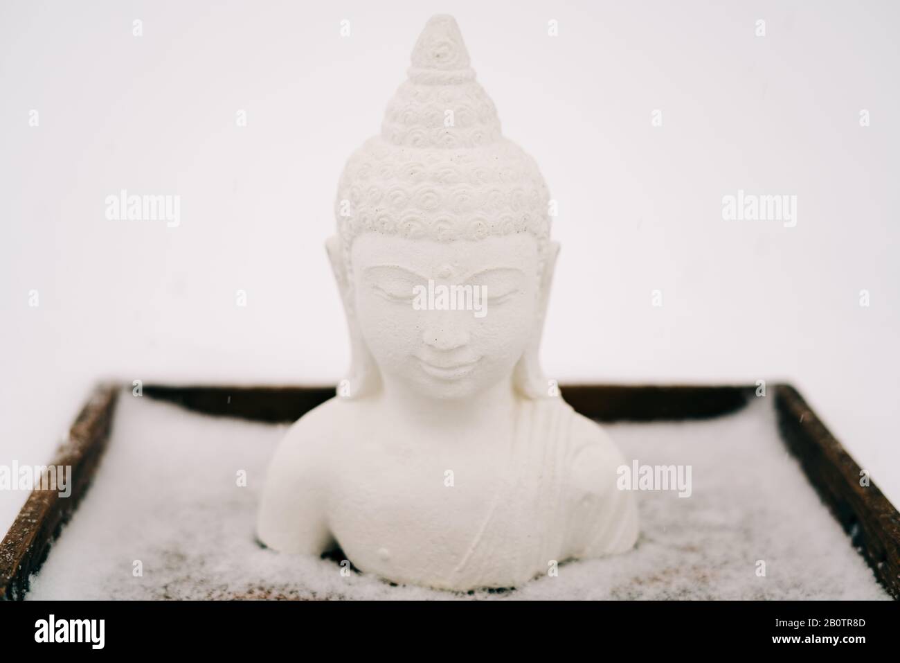 white Buddha figurine made of plaster on a wooden stand during a ...