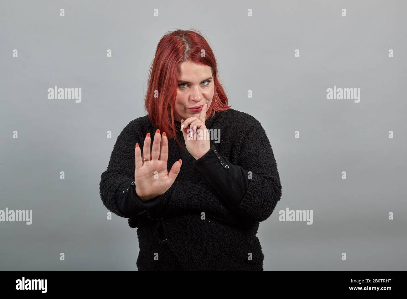 mysterious woman stops with palm hand, stop sign, holds index finger ...