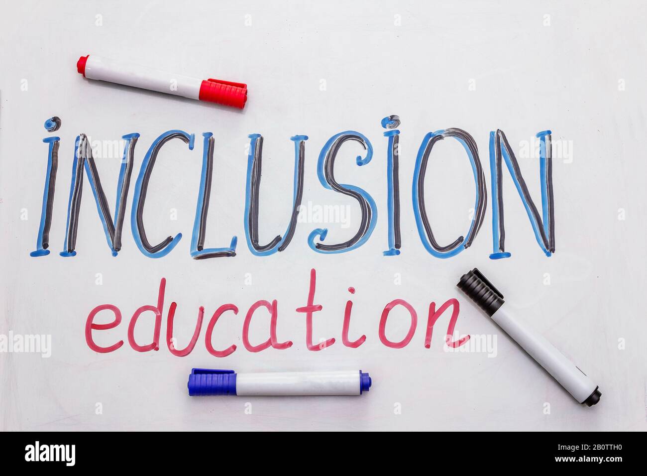 Hand drawn word "inclusion education" on marker board. Blue and black ...