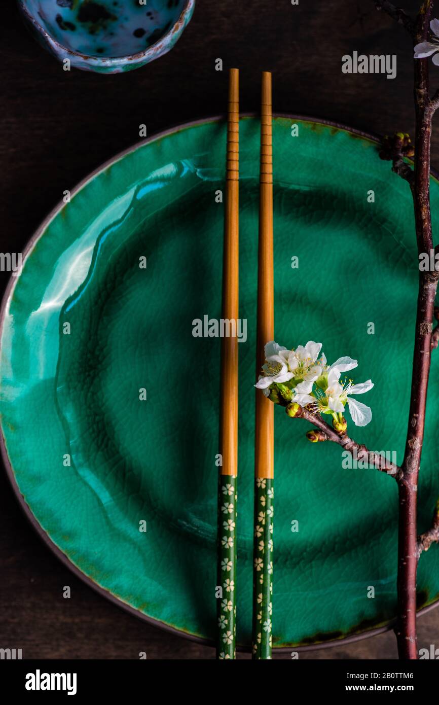 Asian style table setting with cherry blossom and wooden chopsticks ...