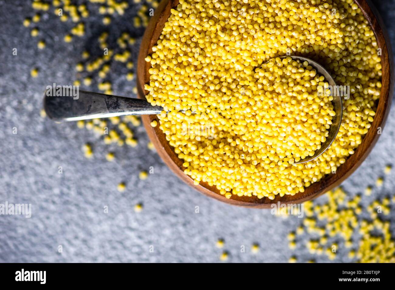 Organic food concept with wooden bowl full of millet cereals on stone ...