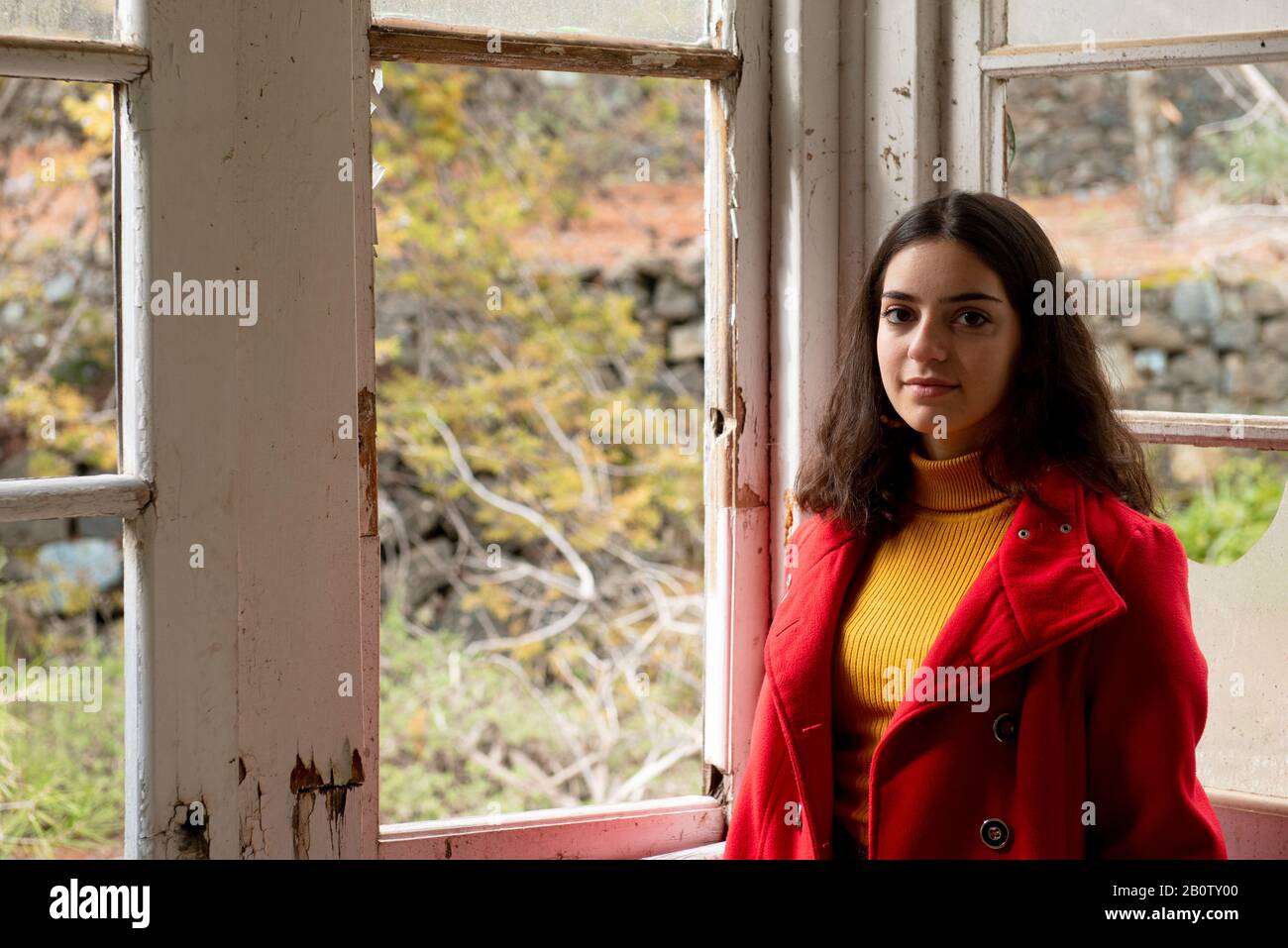 Young beautiful woman dressed in red standing in front of a broken ...