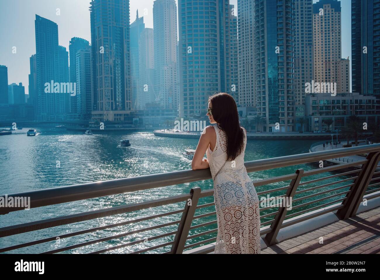 Happy beautiful tourist woman in fashionable summer white dress walking ...