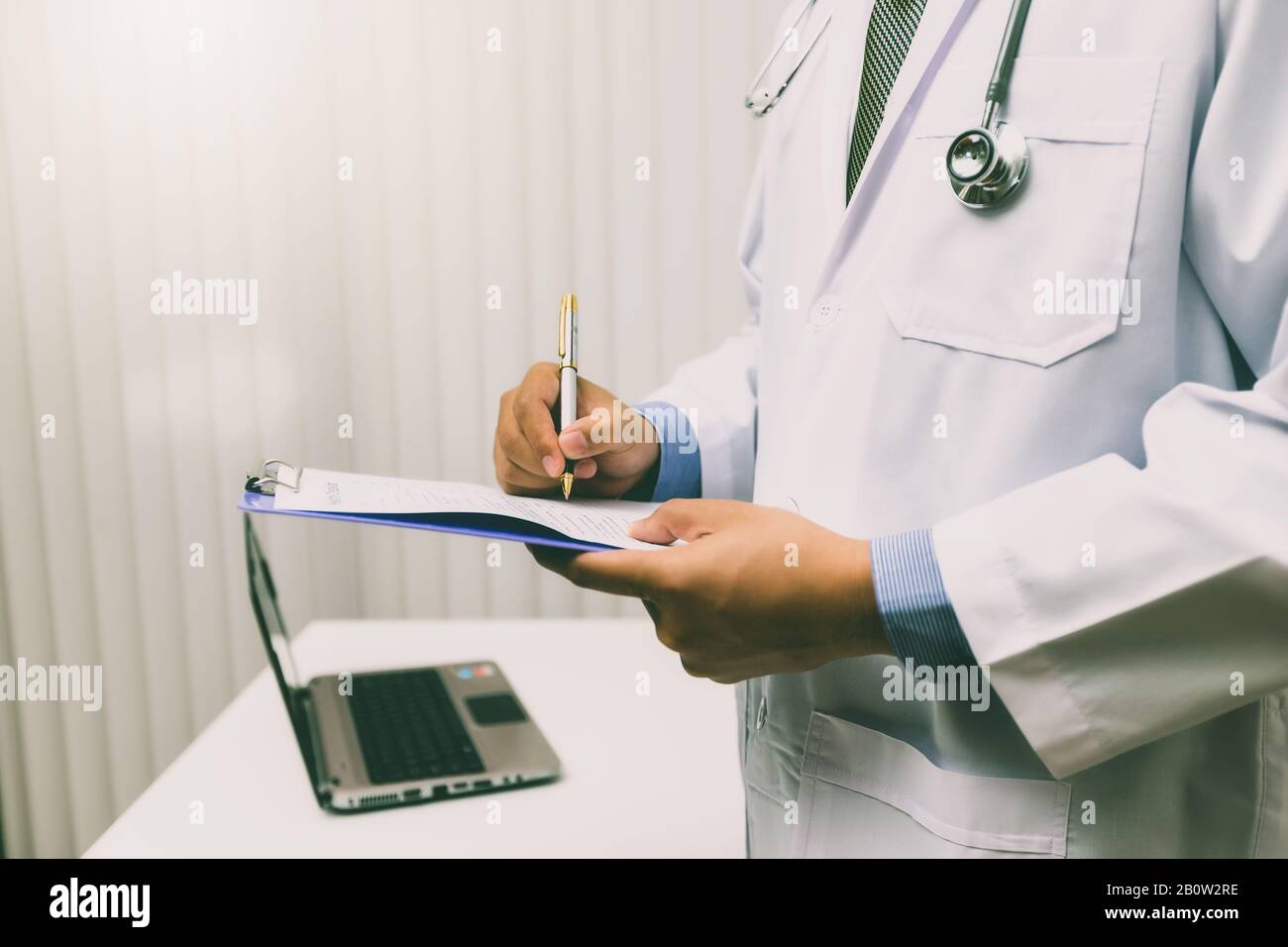 Doctor in gown uniform using a pen write on medical chart. Medicine and ...
