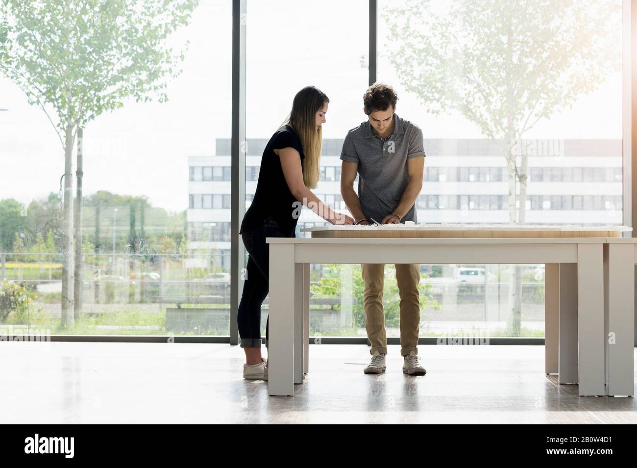 Two young architects standing at a table, working on an architectural ...