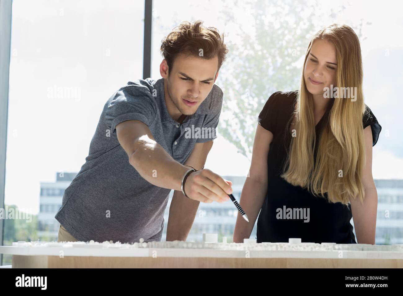 Two young architects standing at a table, working on an architectural ...