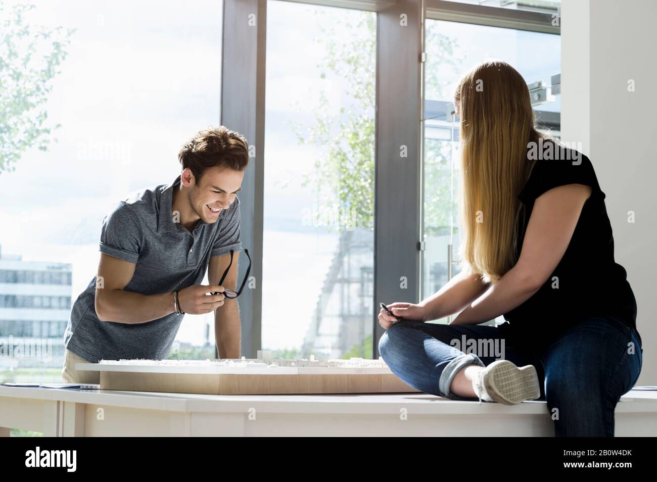 Two young architects standing at a table, working on an architectural ...