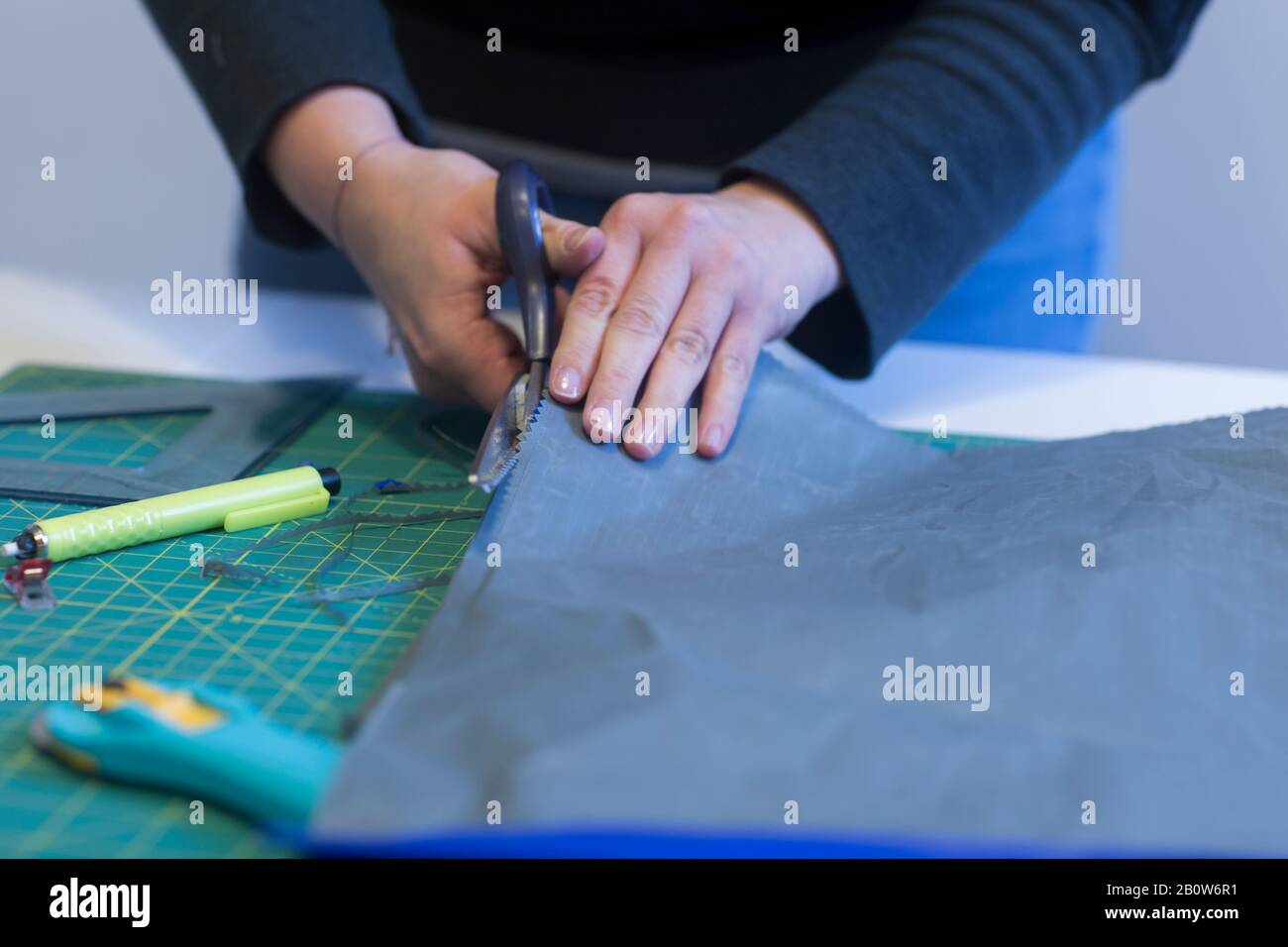 Close up of female tailor cutting blue fabric with scissors Stock Photo ...