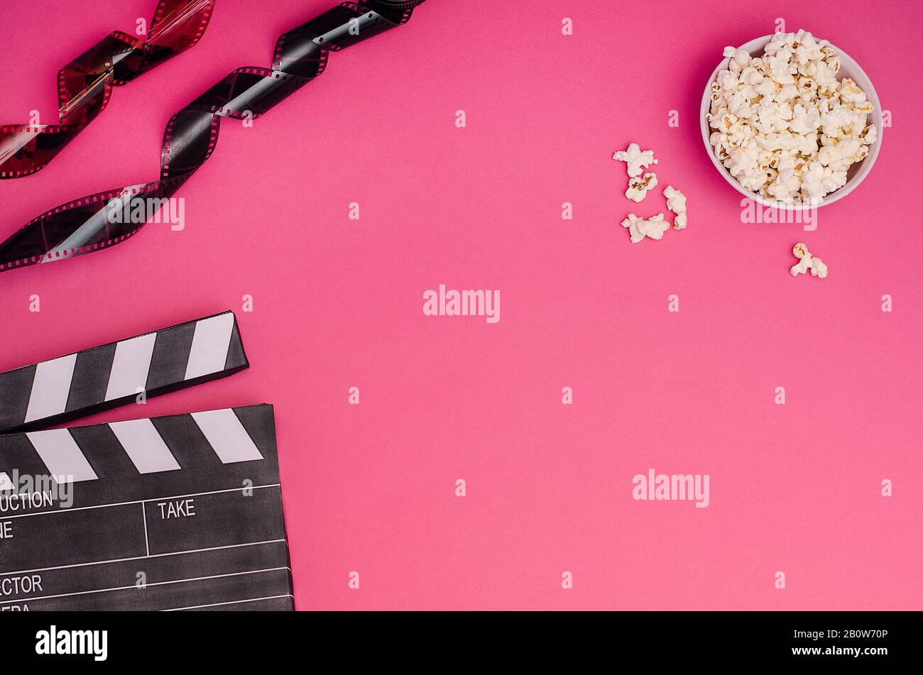 Clapper board with popcorn and film strip on a bright pink background ...