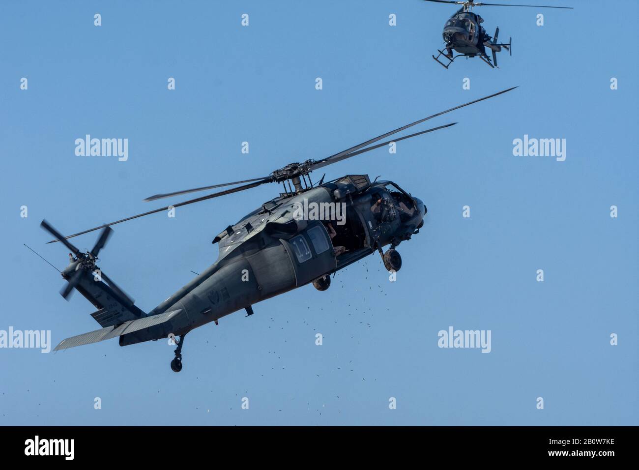 Two Military choppers shooting machine guns in combat and war flying ...