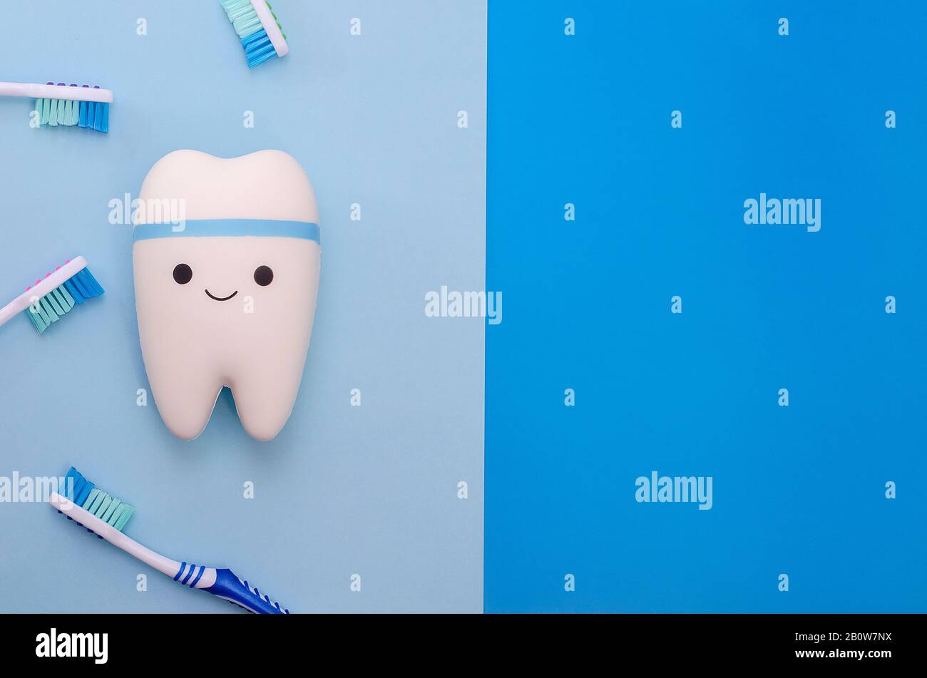 Cheerful smiling tooth on a blue background with toothbrushes with copy ...