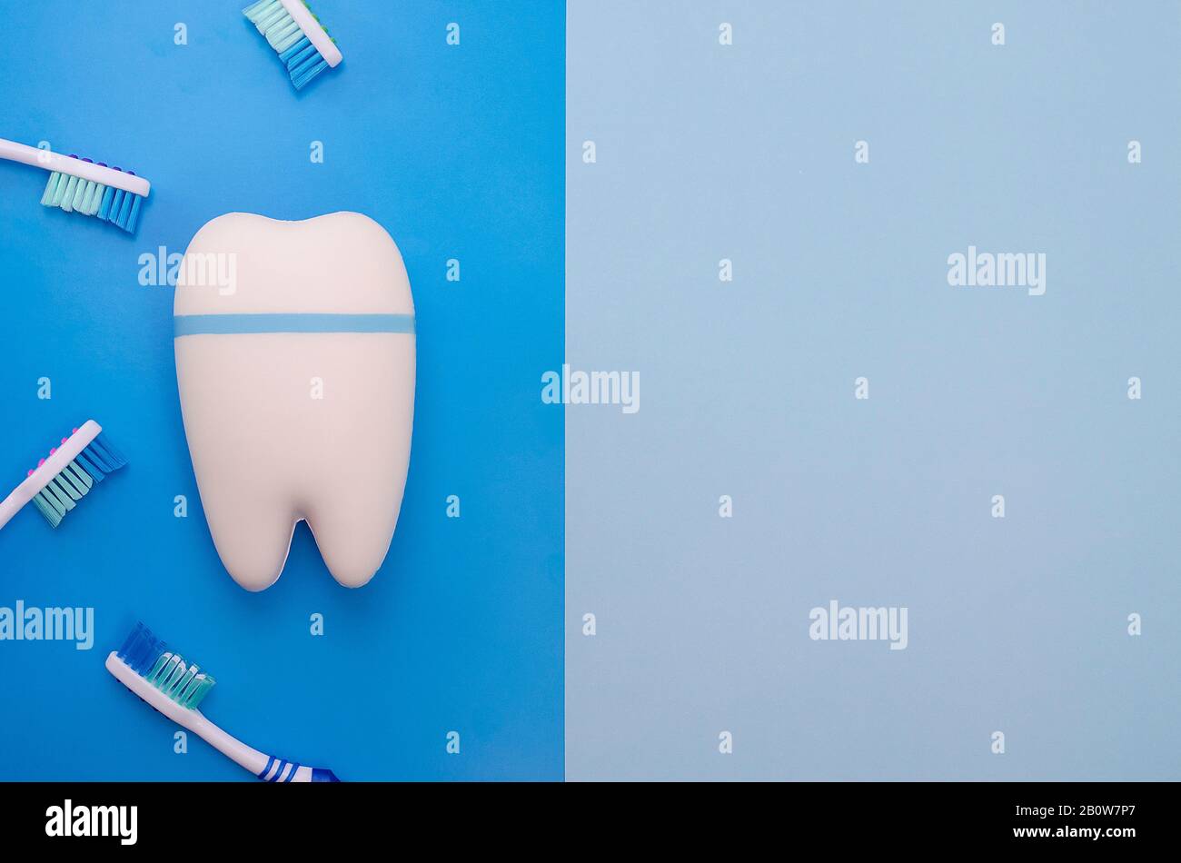 Toy tooth on a blue background with toothbrushes with copy space ...