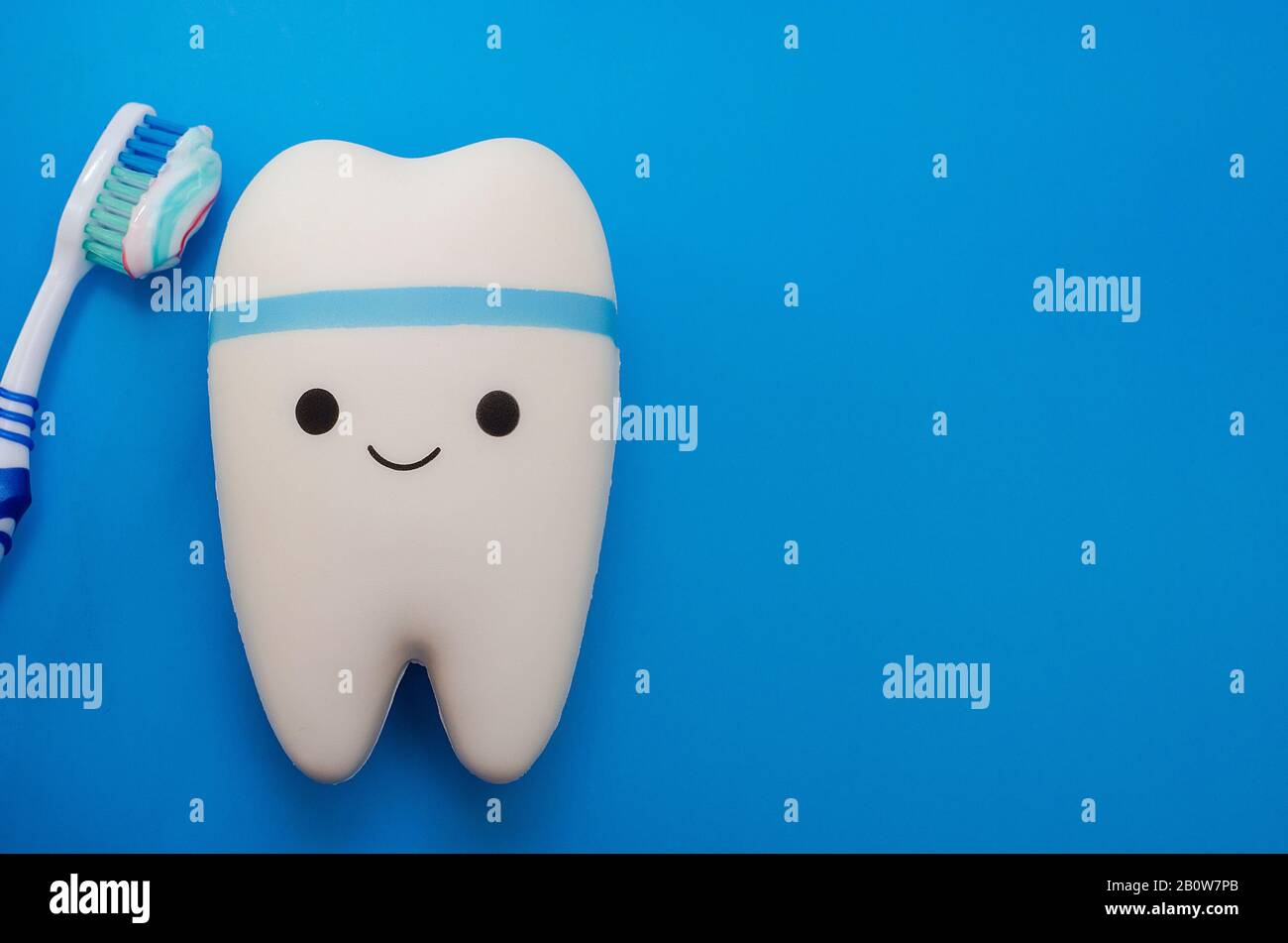 Cheerful smiling tooth on a blue background with a toothbrush with copy ...