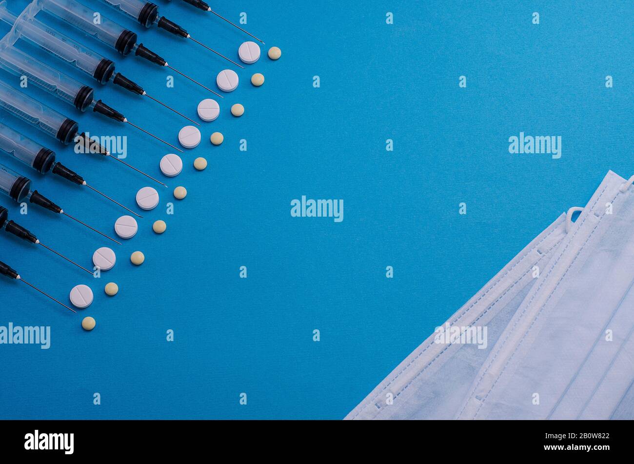 Pills, masks, syringes on a light blue background with copy space. Coronavirus spread. Viral ...
