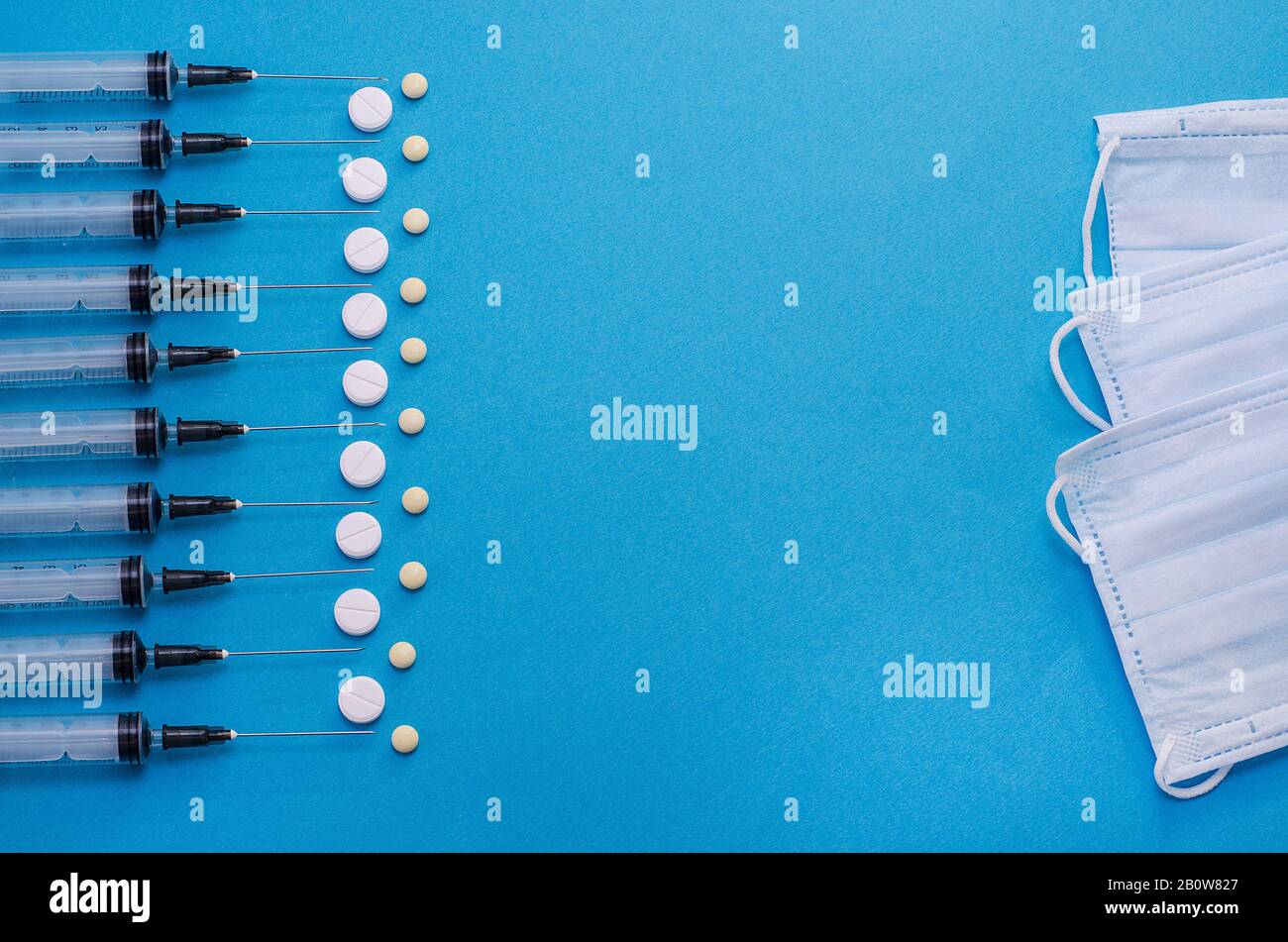 Pills, masks, syringes on a light blue background with copy space. Coronavirus spread. Viral ...