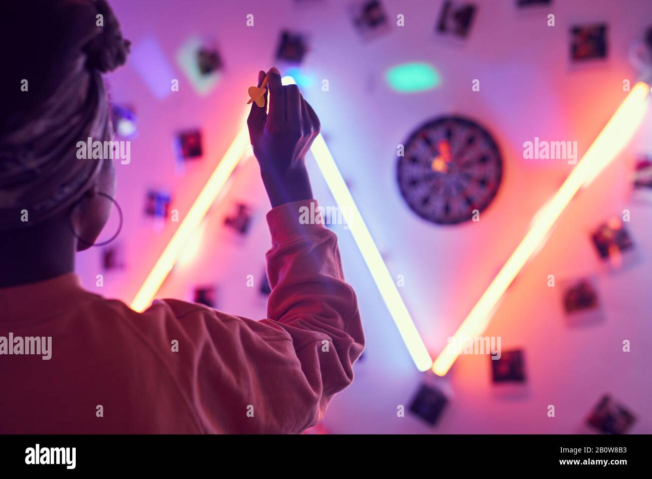 Rear view of African woman throwing dart she playing darts during a ...