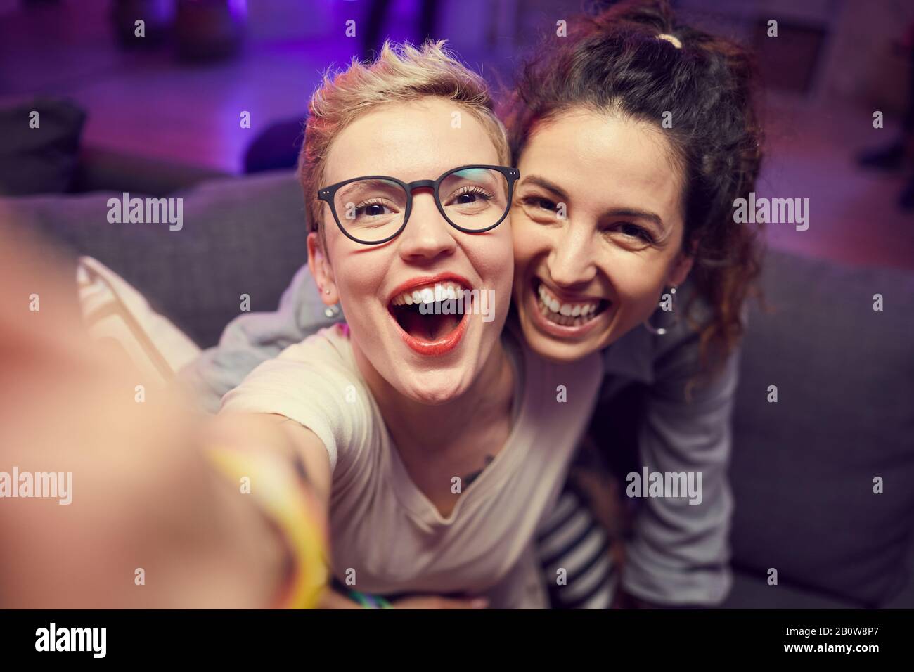 Portrait of two excited friends smiling at camera during selfie ...