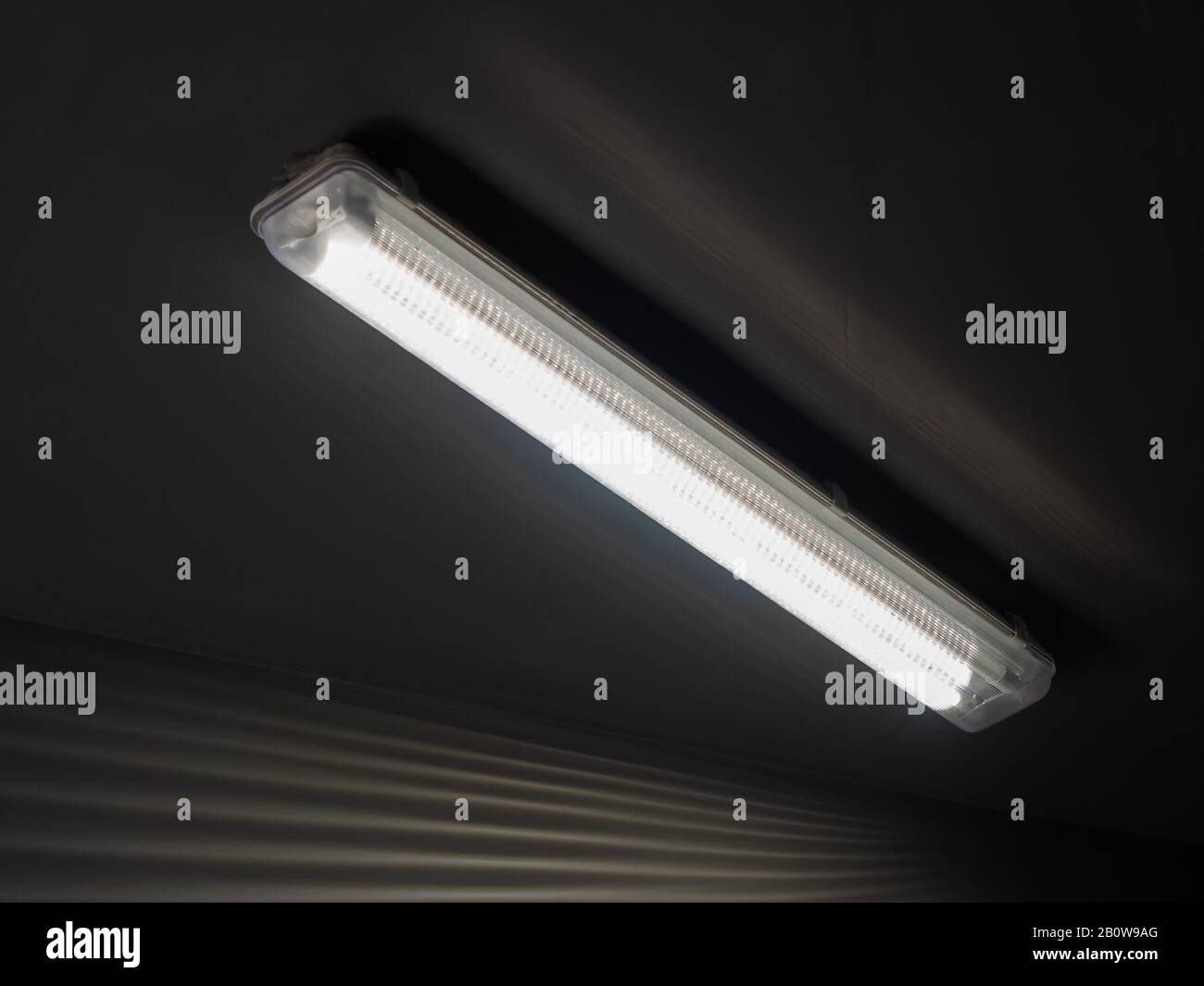 Close-up photo of a long luminous lamp hanging on dark ceiling Stock ...