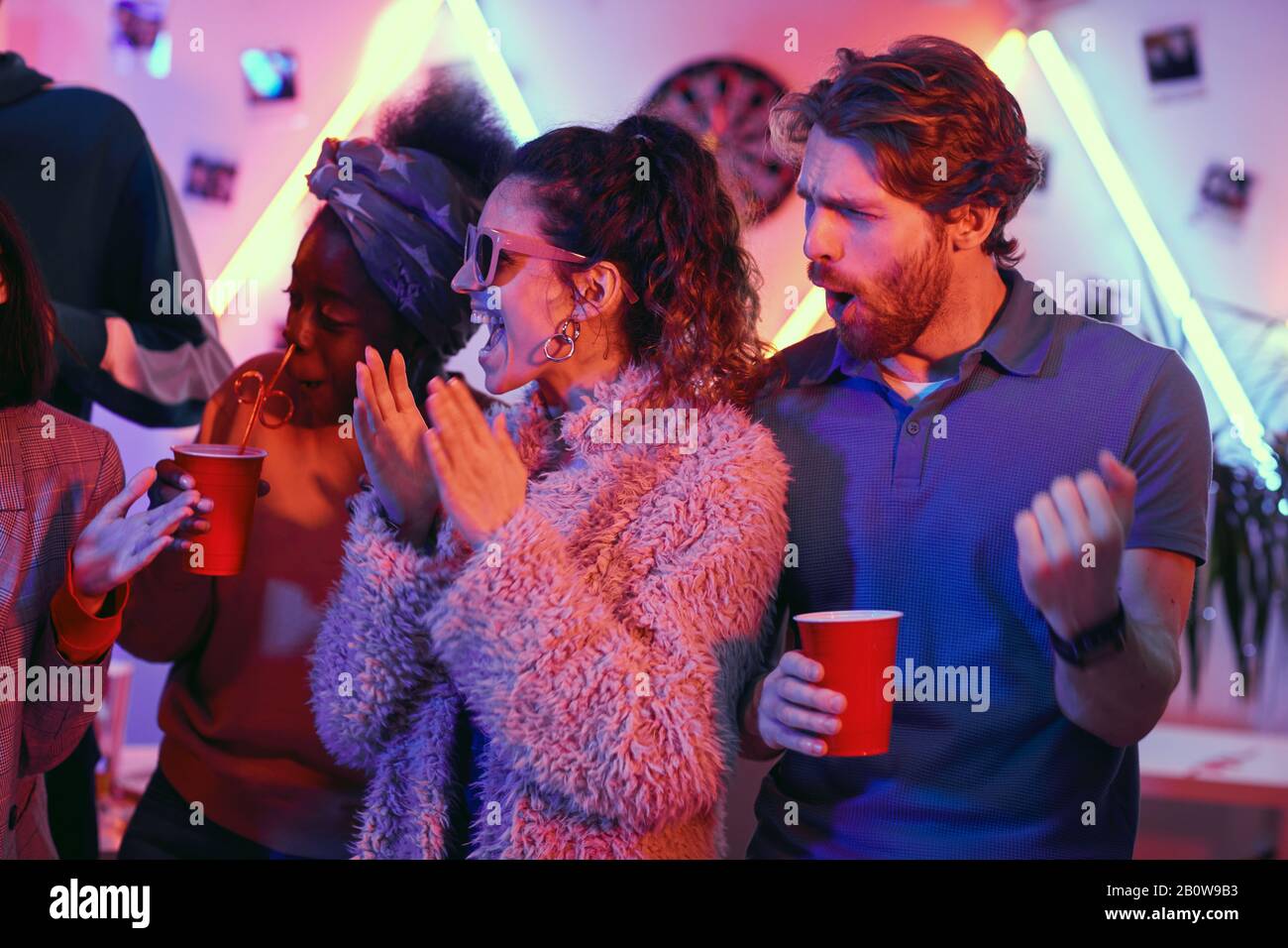 Group of young excited people with drinks having fun with friends at ...