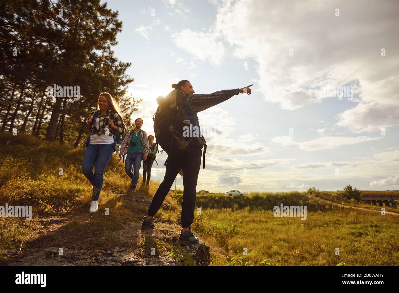 Young people with backpacks walking in the forest Stock Photo - Alamy