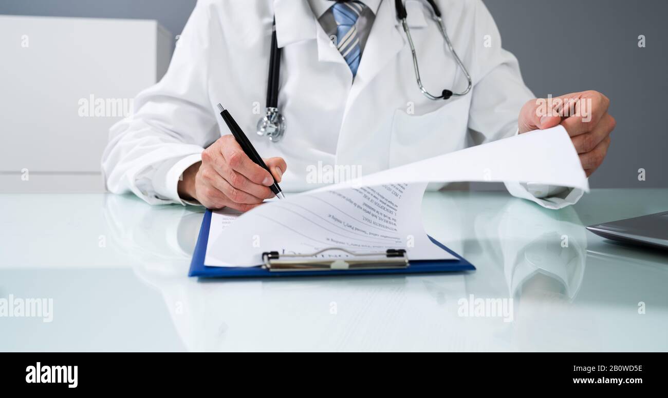Doctor's Hand Signing Document On Desk In Clinic Stock Photo - Alamy