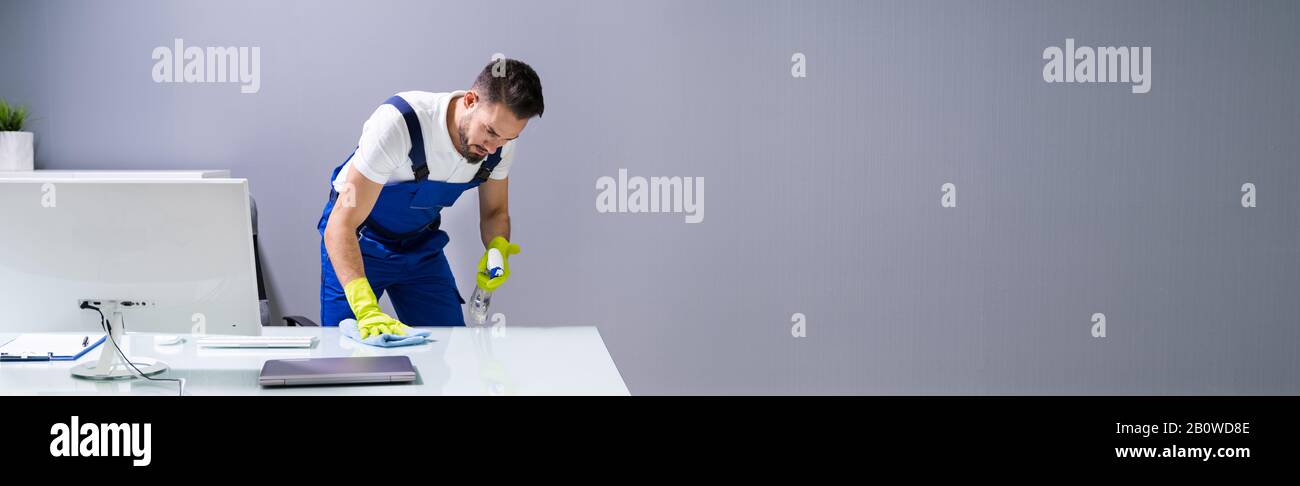Worker Cleaning Computer Desk With Spray And Sponge Stock Photo - Alamy