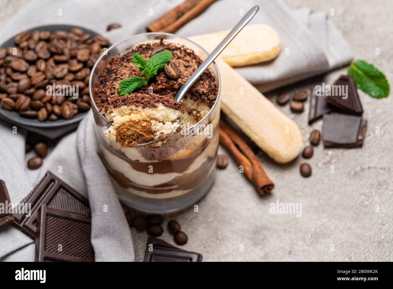 Classic tiramisu dessert in a glass cup, pieces of chocolate and ...